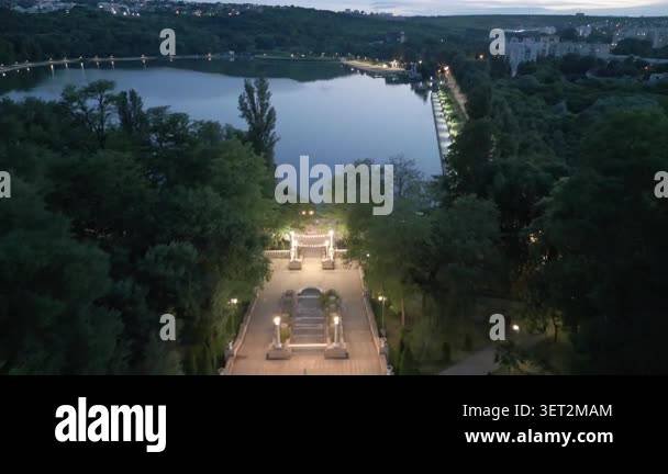 Aerial footage revealing a lakeside park with illuminated paths and ...