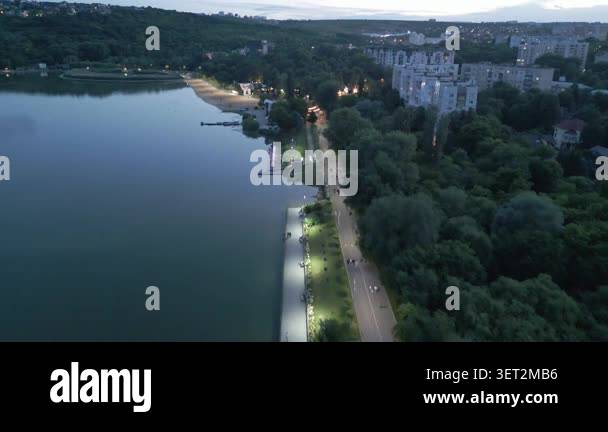 Drone footage capturing a scenic lakeside boulevard with illuminated ...