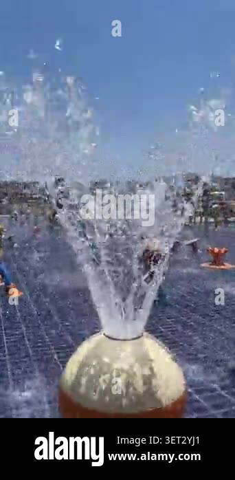 Water fountain spray on a tiled surface at a sunny outdoor splash park ...