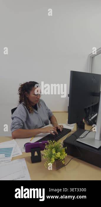 Businesswoman with curly hair concentrating while typing on a computer ...