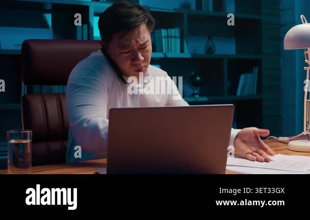 Frustrated aggressive Asian business man talking phone with papers ...
