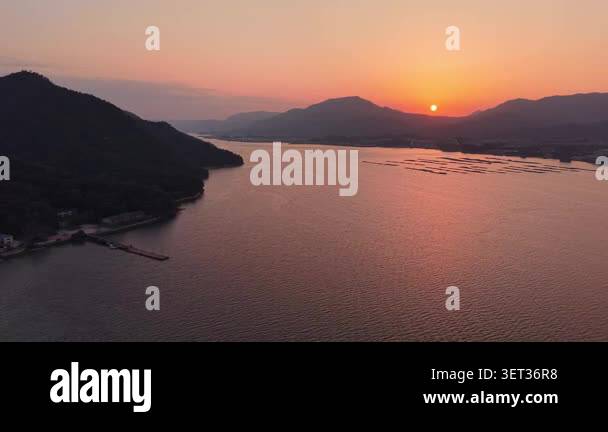 An aerial view of a golden sunset over the calm bay and islands of the ...