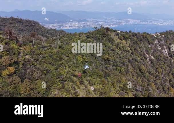 An aerial view of a forested mountain with a ropeway cable car above ...