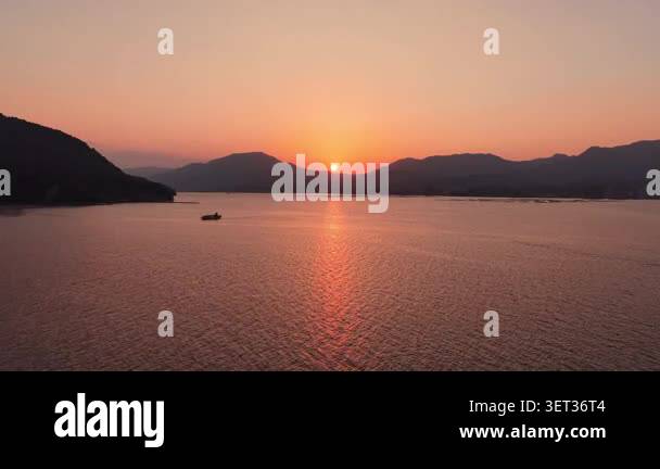 An aerial view of a golden sunset over the calm bay and islands of the ...