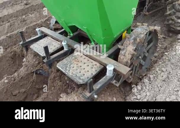 green potato planter machine attached to tractor working in ...