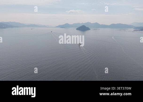 An aerial view of a boat crossing the calm hazy Seto Inland Sea between ...