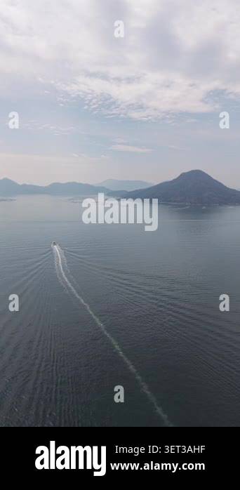 An aerial view of a boat crossing the calm hazy Seto Inland Sea between ...