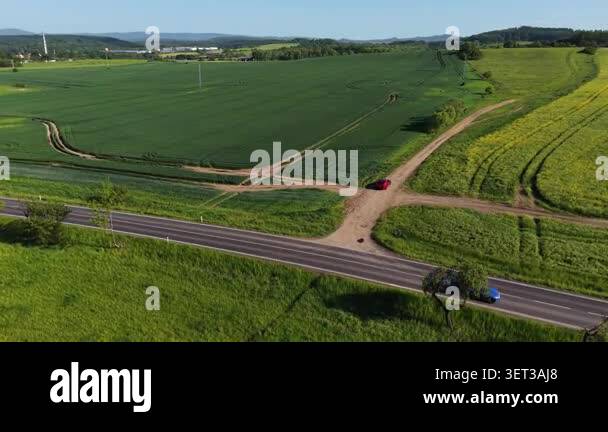 An aerial view of a road winding through the green fields and forests ...
