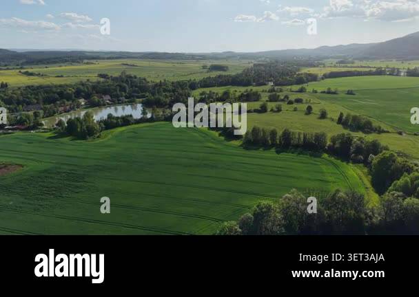 An aerial view of green rolling fields, meadows and forested hills of ...