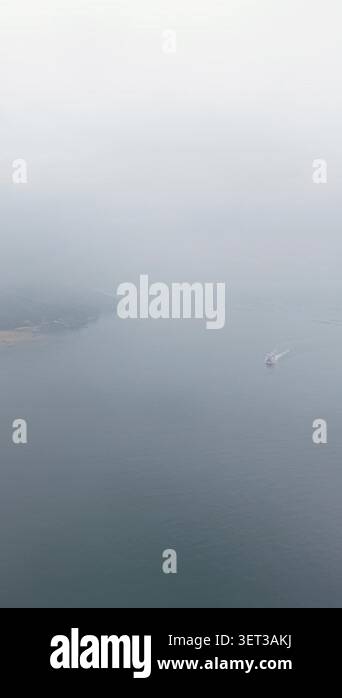 An aerial view of a misty island coastline, forested mountains and the ...