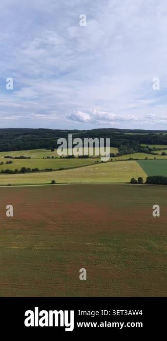 An aerial view of green rolling fields, meadows and forested hills of ...