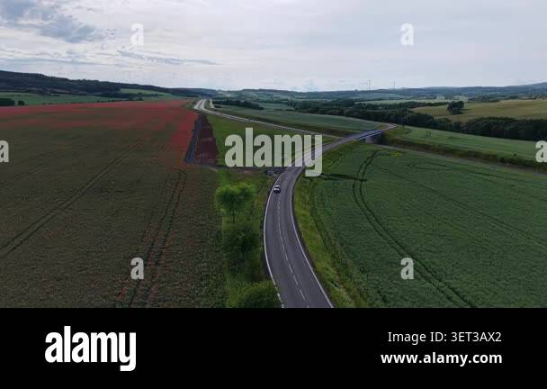 An aerial view of a road winding through the green fields and forests ...