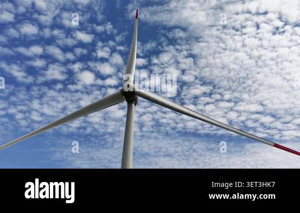 An aerial view of wind turbines standing in green fields under a blue ...