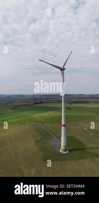 An aerial view of wind turbines standing in green fields under a blue ...