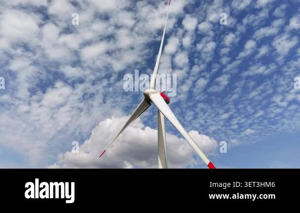 An aerial view of wind turbines standing in green fields under a blue ...