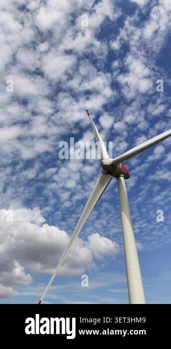 An aerial view of wind turbines standing in green fields under a blue ...