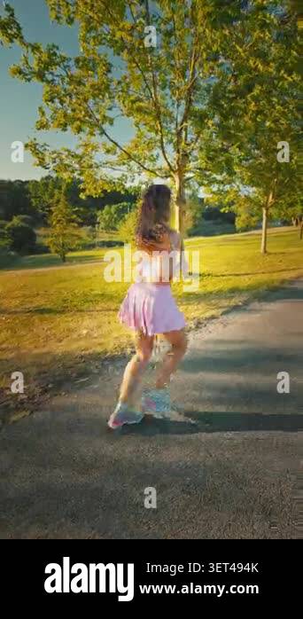 Fit young woman jogging on a paved path in a park during a sunny day ...
