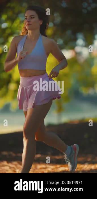 Beautiful sporty woman with long curly hair jogging in a park during a ...