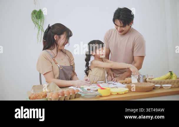 Happy Asian family baking together in kitchen, parents teaching child ...