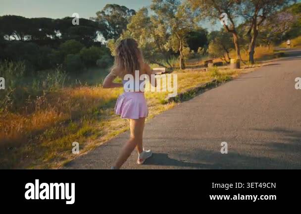 A person jogs on a path in a park during the evening. The sun sets ...