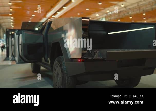 An electric truck is on display at an auto show. People walk around and ...