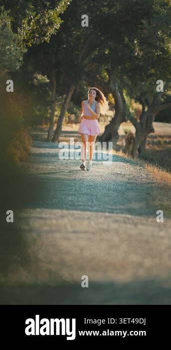 Young athletic woman with long hair jogging on a path during a ...