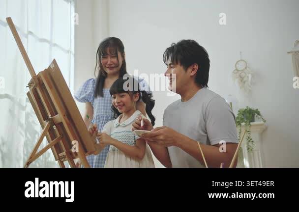 Asian family enjoying painting together at home. father, mother, and ...