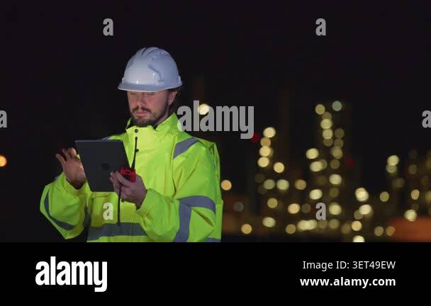 Petrochemical engineers use a tablet and radio to monitor refinery ...