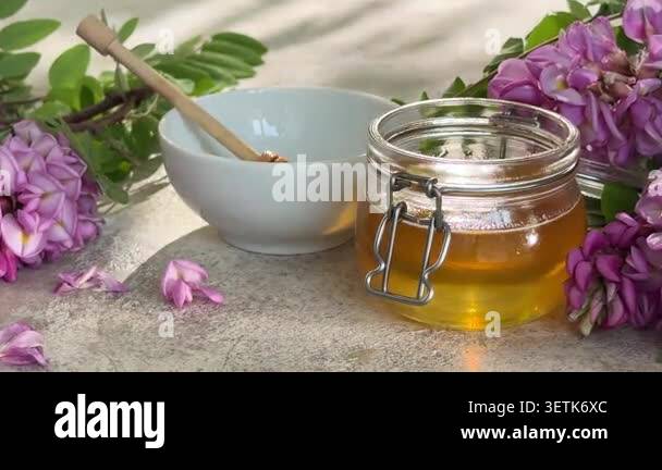 Organic acacia honey in glass jars with beautiful pink acacia flowers ...