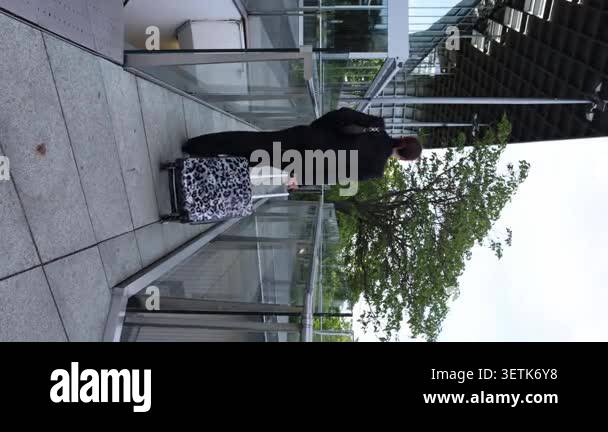 A person walks on a pathway towards a building while pulling a bag ...
