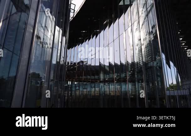Workers are seen at a modern building in a city as sunlight shines off ...