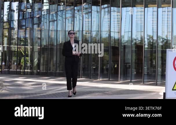 A woman in a suit walks towards the camera in a city setting. She moves ...