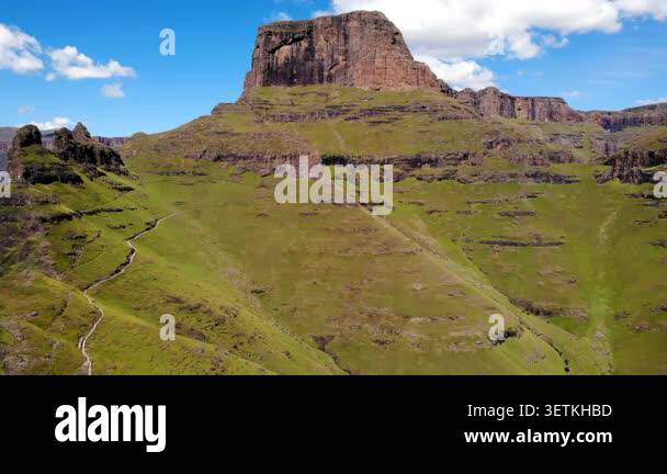 Wide scenic view of a rugged mountain rising over grassy slopes and ...