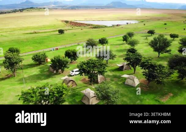 Wide daytime aerial view of a remote campsite in open green savanna ...