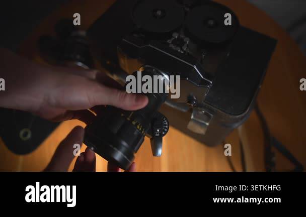 Close-up of a vintage film projector centered on a wooden table, with a ...