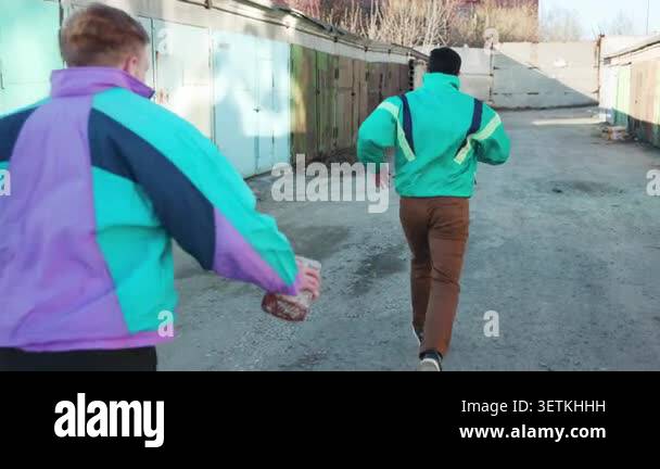 Rear view of two men walking along a confined service lane beside ...
