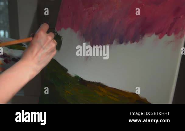 Close view of a hand using a paintbrush to apply thick magenta and ...