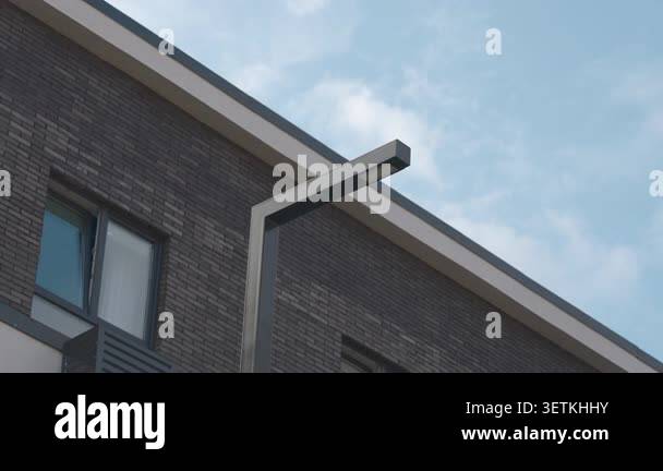 Upward view of a contemporary brick home with a sloped roof, windows ...