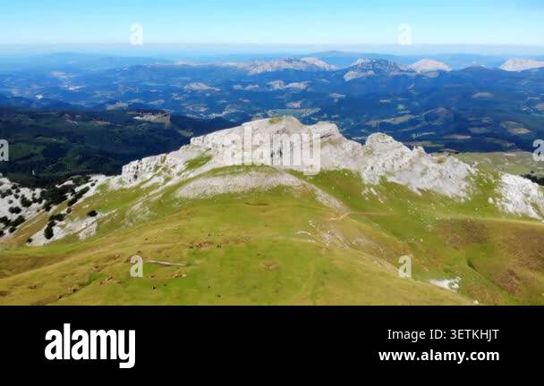 Wide aerial view of a rocky mountain ridge rising above rolling green ...