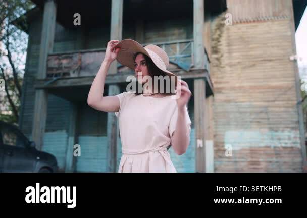 Young woman in a light dress stands outdoors in soft daylight ...