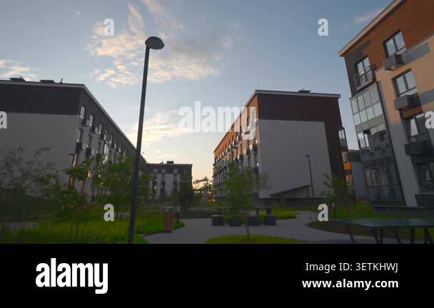 A calm residential courtyard between modern apartment buildings, with a ...