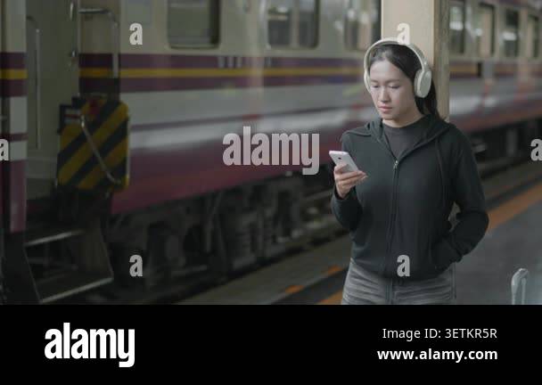 Woman wearing headphones using smartphone at station Stock Video ...