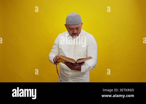 Devout Muslim Man Reading the Holy Quran on a Yellow Background ...
