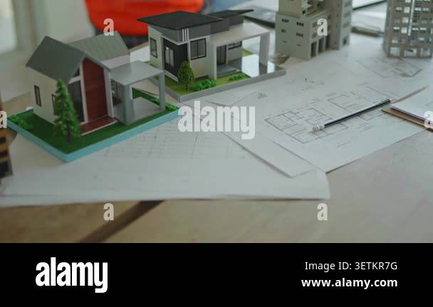 Miniature houses placed near architectural blueprints while architects ...
