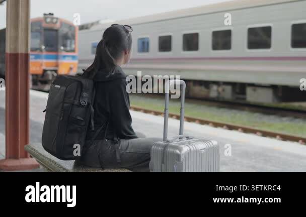 Woman waiting beside suitcase at train station Stock Video Footage - Alamy