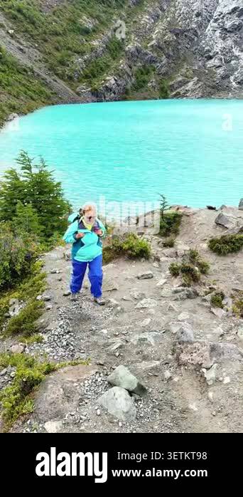 A female hiker climbing the trail by the lagoon and glacier Huemul in ...