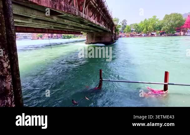 A low-angle perspective shows the underside of a weathered iron bridge ...