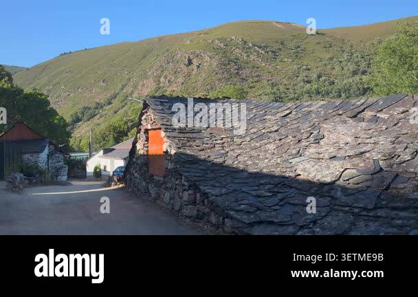 Stone wall with orange door, mountainous backdrop. Path leads through ...