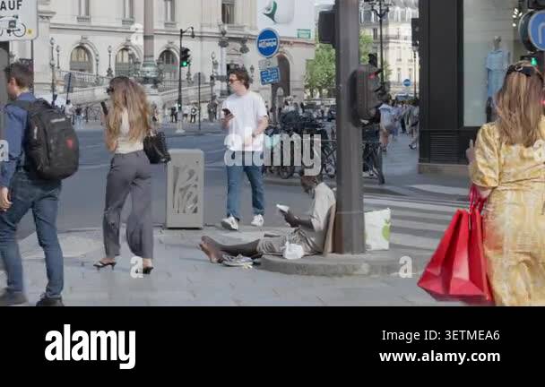 PARIS, FRANCE, JUNE 4, 2026 A homeless man sits on a city pavement as ...