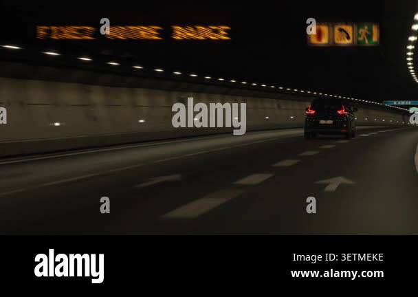 Several automobiles drive through an underground highway tunnel past ...